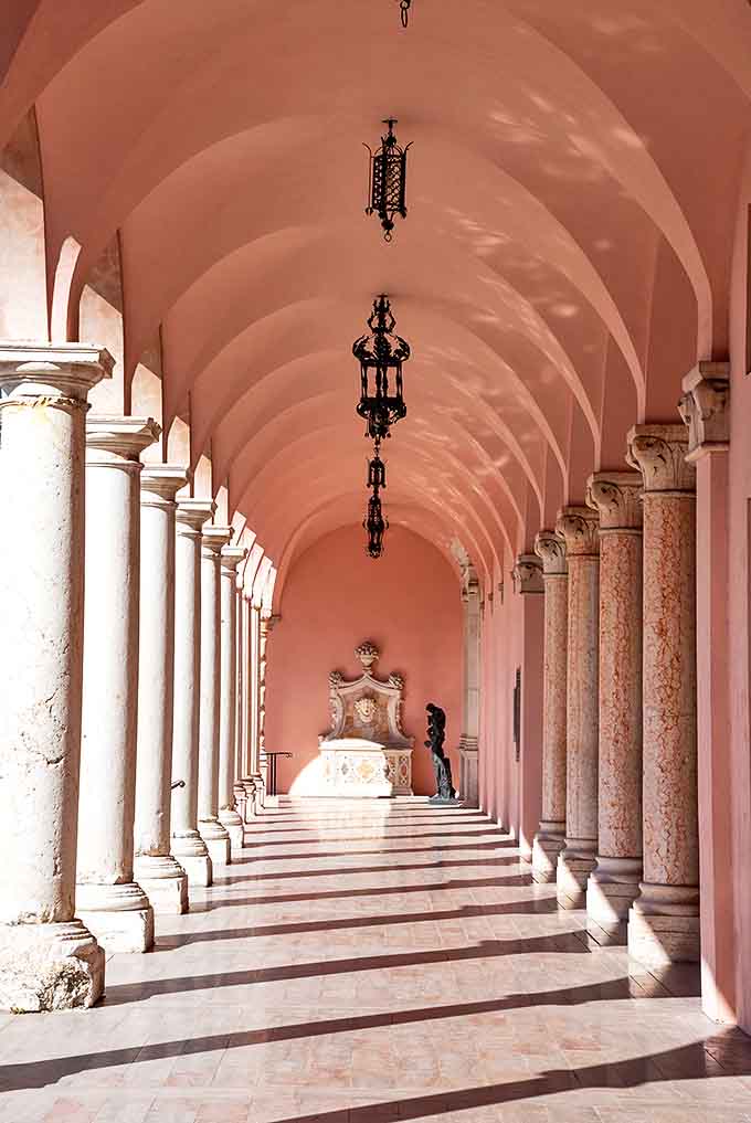 The hallway's pink arches create a rhythm of light and shadow that photographers dream about and Instagram feeds desperately need.