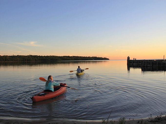 Sunset Kayaking: Paddlers glide through glass-like waters as the day's final light paints everything in warm gold – pure Michigan magic captured in a moment.