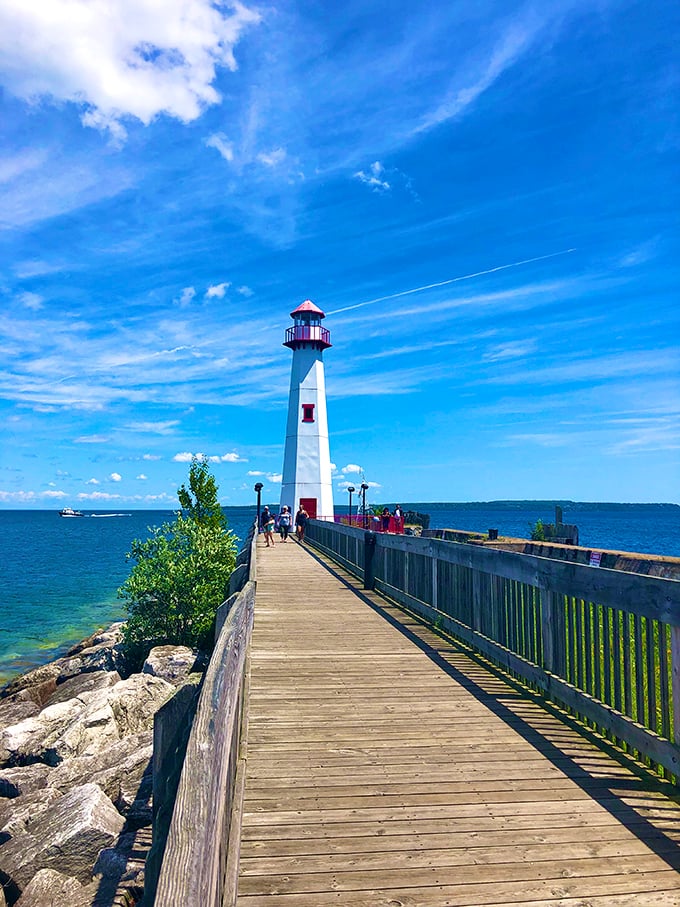 The lighthouse stands guard at the harbor entrance, a red-capped sentinel guiding vessels safely to shore while providing the perfect backdrop for vacation selfies.