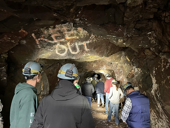 Modern-day explorers examine century-old markings left by miners who never imagined their workplace would become a tourist attraction.