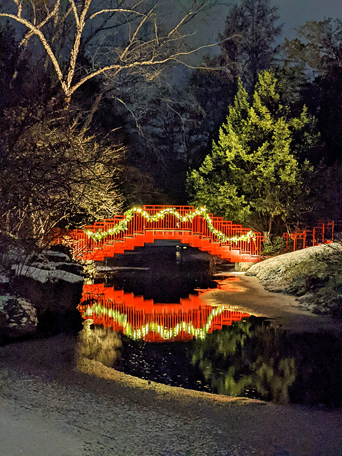 The iconic red bridge glows like a ember against the night, its reflection creating a perfect fiery circle in the still water.