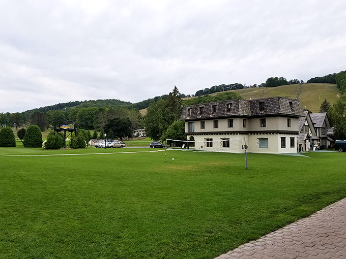 The expansive green lawn offers a peaceful respite from water activities, with the charming resort buildings creating a picturesque backdrop.