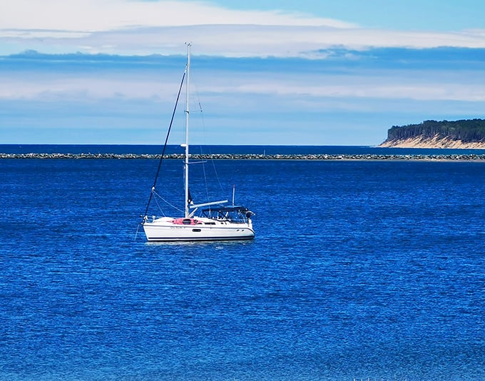 A lone sailboat finds solitude on Superior's vast blue canvas, dwarfed by the immensity of water meeting sky.