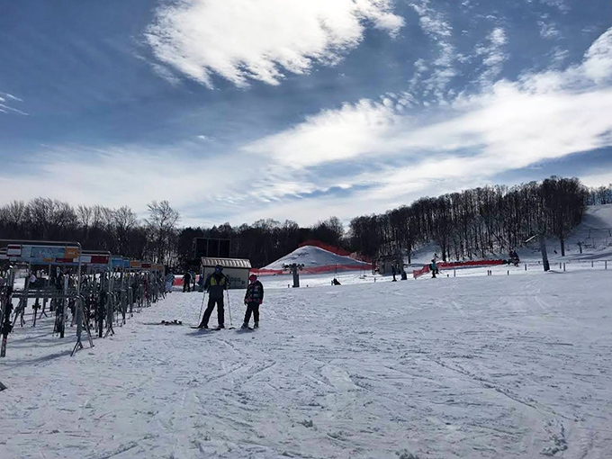 Perfect Michigan winter day: blue skies, fresh powder, and happy skiers carving their way down meticulously groomed slopes.