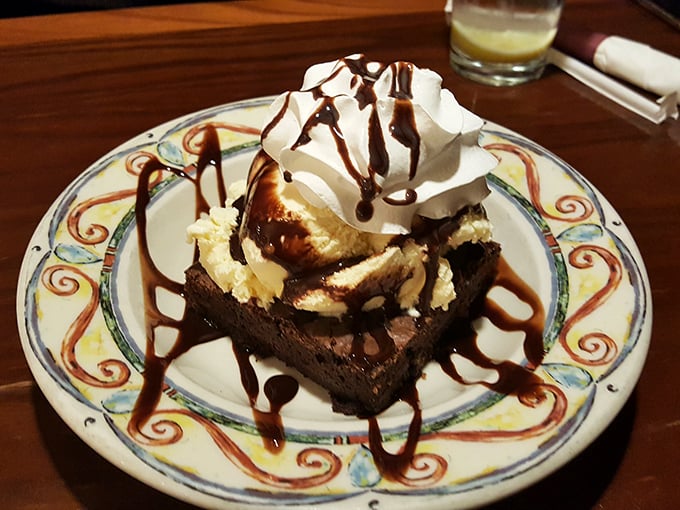 A brownie dessert that laughs in the face of restraint, topped with ice cream and whipped cream in delicious defiance.