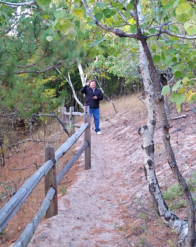A hiker enjoys the winding trail through sandy terrain, where each step reveals the delicate balance of dune ecosystems.