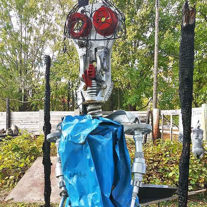 Red circular eyes peer out from this metallic sentinel, its body assembled from parts that once served entirely different purposes.