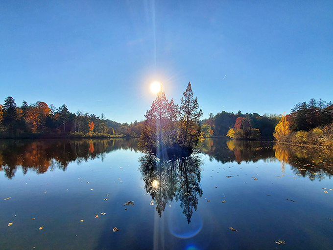 Morning mist rises from the lake's surface, creating an ethereal scene where reality and reflection merge into something almost magical.