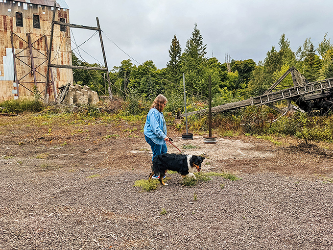 A visitor and canine companion explore the grounds, adding a sense of scale to the massive industrial ruins that dominate the landscape.