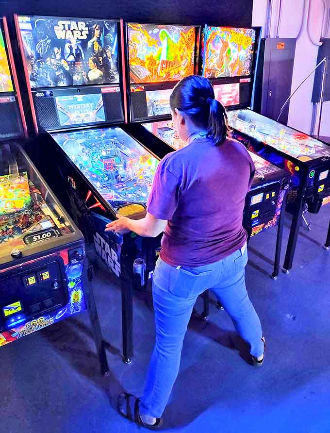 Woman Playing Pinball Lost in concentration, this pinball wizard demonstrates the timeless appeal of silver balls, flashing lights, and the perfect flipper timing.
