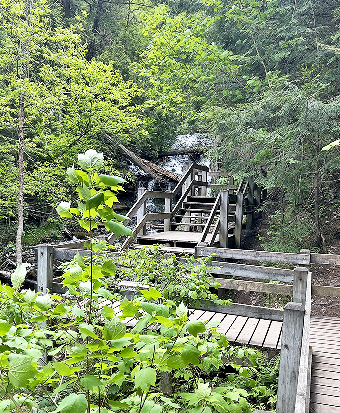 Rustic wooden stairs lead adventurers closer to the falls' misty embrace, each step building anticipation for the view ahead.