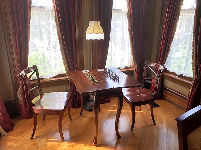 Chess Table Nook: Sunlight streams through lace curtains onto a game where time slows down and strategic thinking replaces digital distractions.