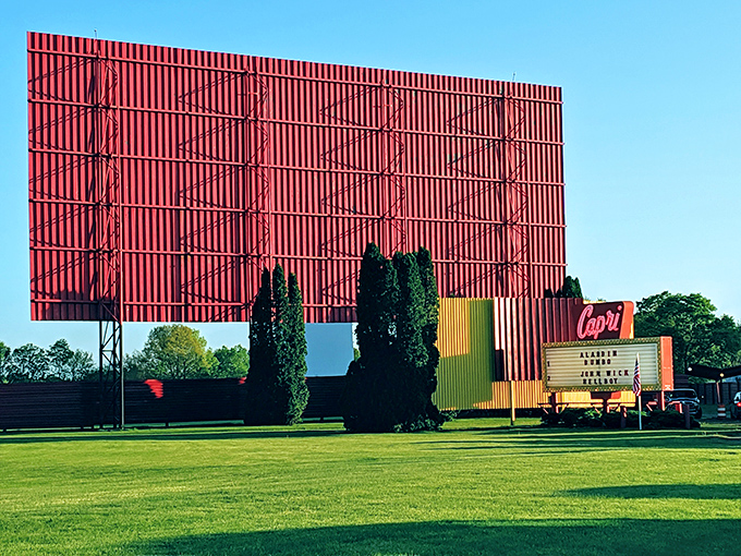 The iconic red screen tower of the Capri Drive-In stands tall against blue skies, a monument to America's love affair with automobiles and movies.