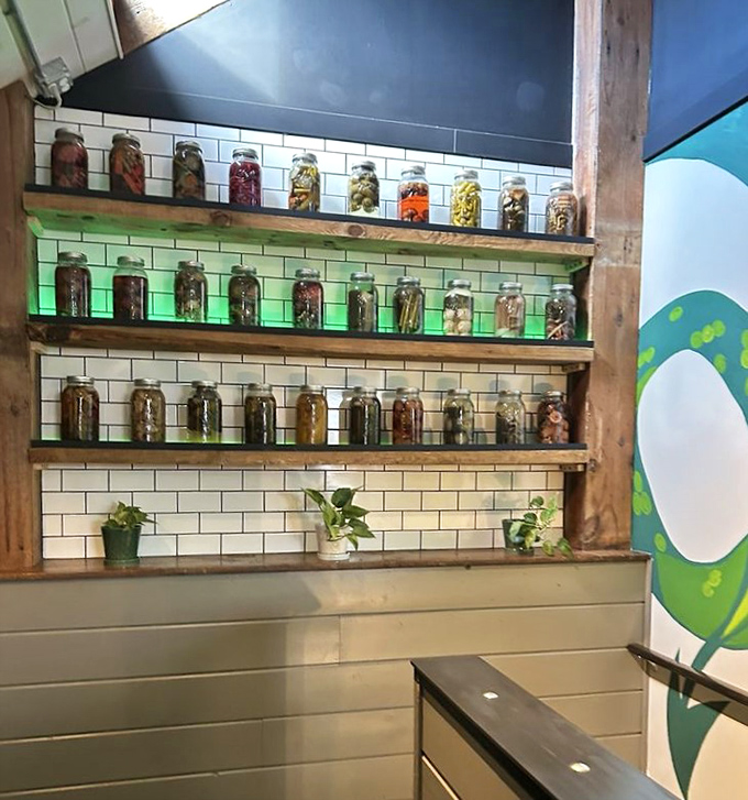 Mason jars of pickled treasures line illuminated shelves like edible art installations &ndash; a preview of flavors waiting in your sandwich.