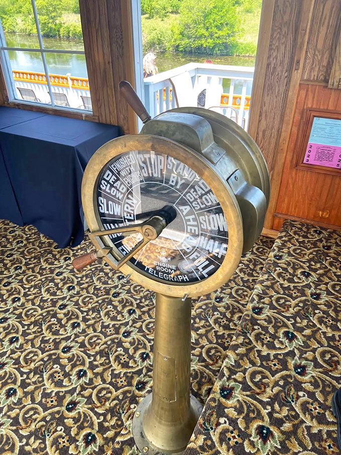 The vintage engine order telegraph stands as a functional museum piece, connecting modern passengers to riverboat history.