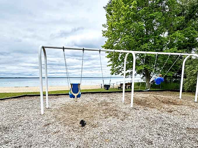 Empty swings sway gently in the lake breeze, waiting for children to return from their adventures in the shallow waters.