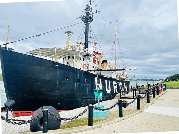 The meticulously preserved Huron vessel stands as a proud reminder of Great Lakes maritime heritage, its black hull contrasting dramatically with the blue water.