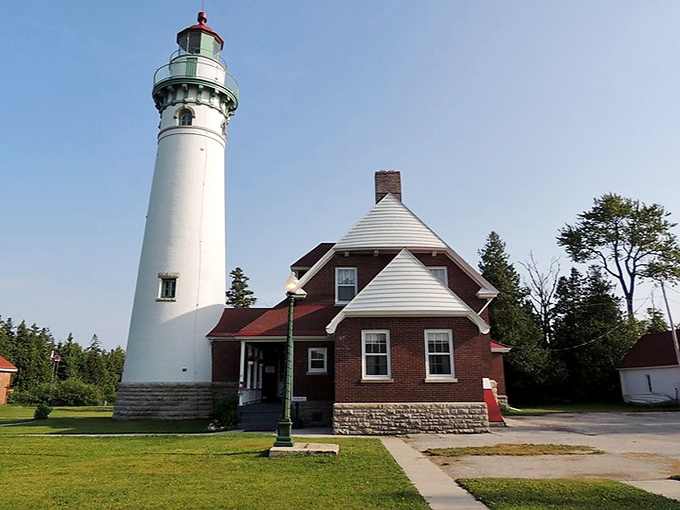 Classic architecture meets functional design in this timeless scene of the keeper's house and towering lighthouse against a clear Michigan sky.