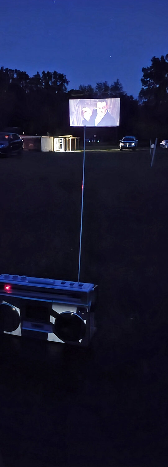 As darkness falls completely, the illuminated screen becomes the center of the universe, casting its glow over a field of upturned faces.