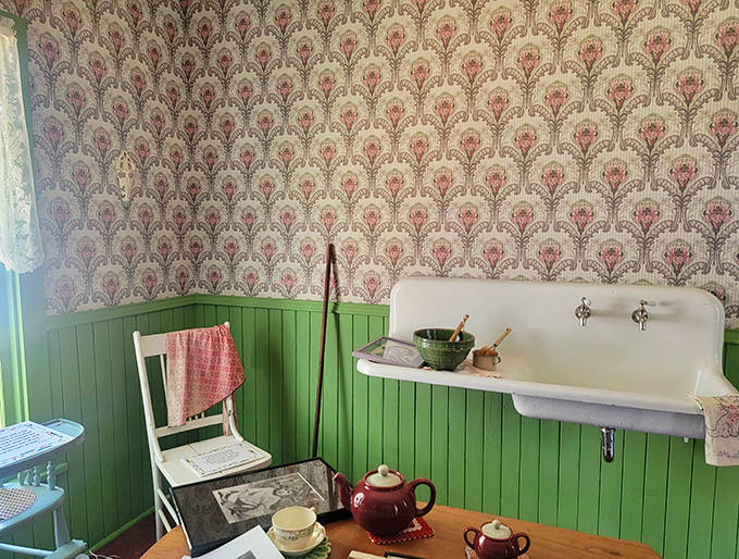 The restored washroom with its vintage sink and green wainscoting captures the simple domestic details of early 20th century Midwestern life.