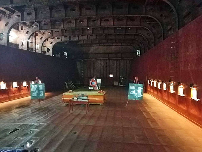 The cavernous cargo hold, once filled with iron ore, now serves as an atmospheric exhibition space. The curved steel ceiling creates an almost cathedral-like ambiance.