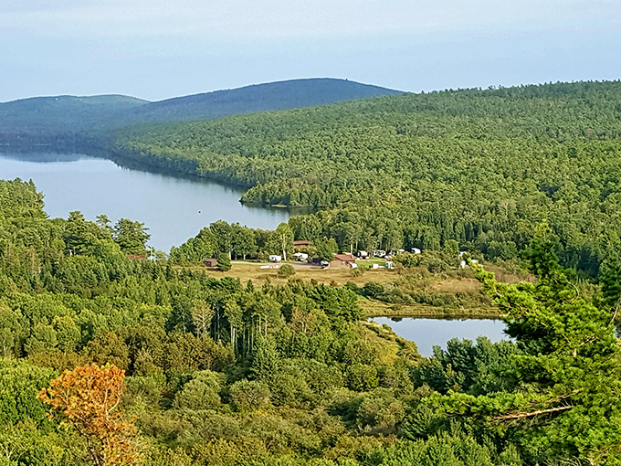 Summer's emerald tapestry stretches to the horizon, where two lakes shimmer like jewels nestled in Michigan's wild northern crown.