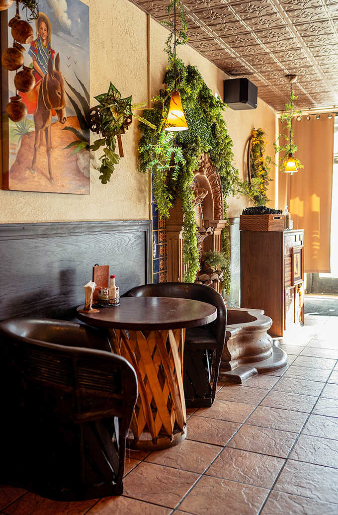 Intimate corner seating surrounded by lush plants and traditional artwork creates the perfect spot for date night or deep conversations over deep flavors.
