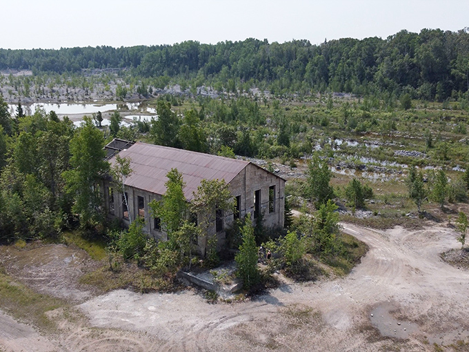 Aerial perspective reveals the quarry's footprint on the landscape, where abandoned buildings stand like islands in a sea of returning wilderness.