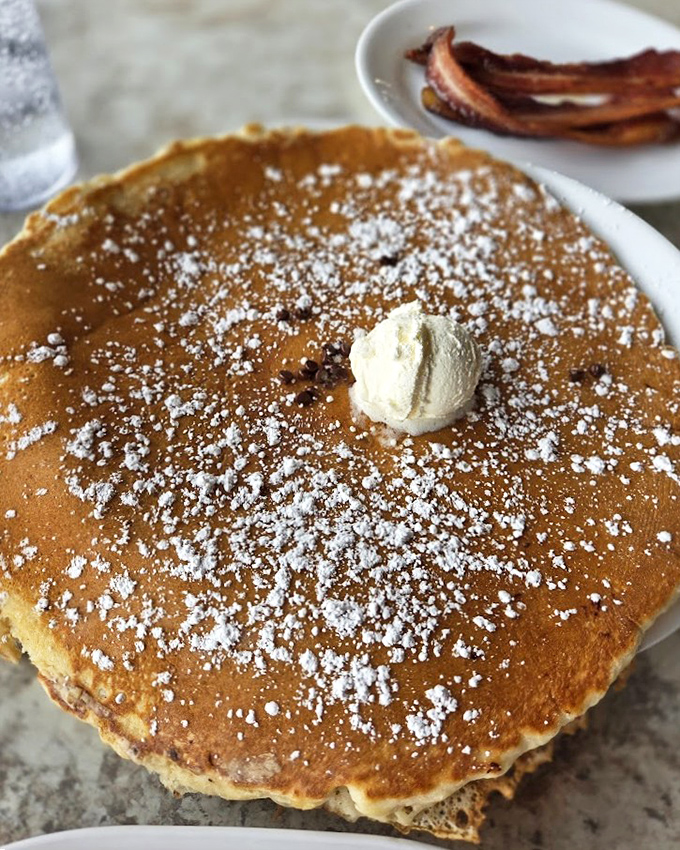 A perfectly golden pancake dusted with powdered sugar and butter, ready to make your morning absolutely spectacular.