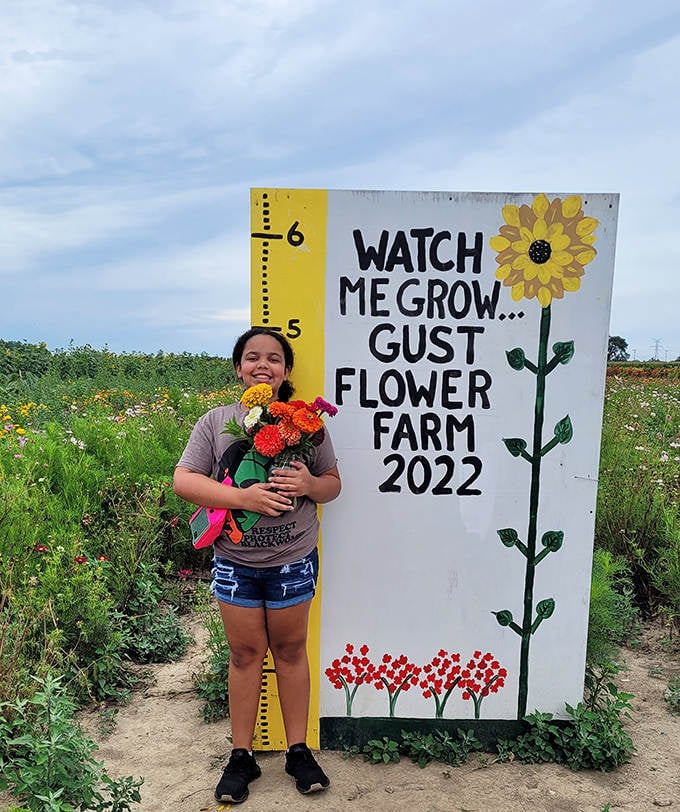 A young visitor measures her height against nature's yardstick, clutching a bouquet of personally picked blooms with unmistakable pride.