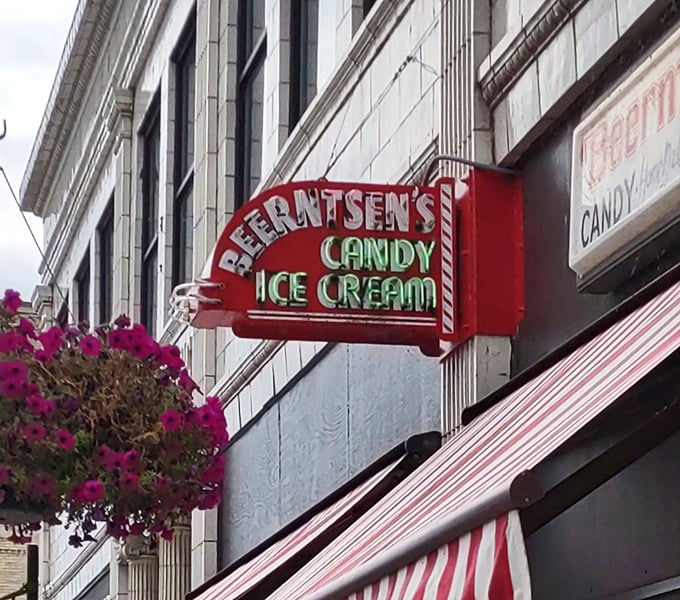 The neon promise of "CANDY ICE CREAM" glows against the building – a beacon of sweetness that's been guiding sugar-seekers for generations.