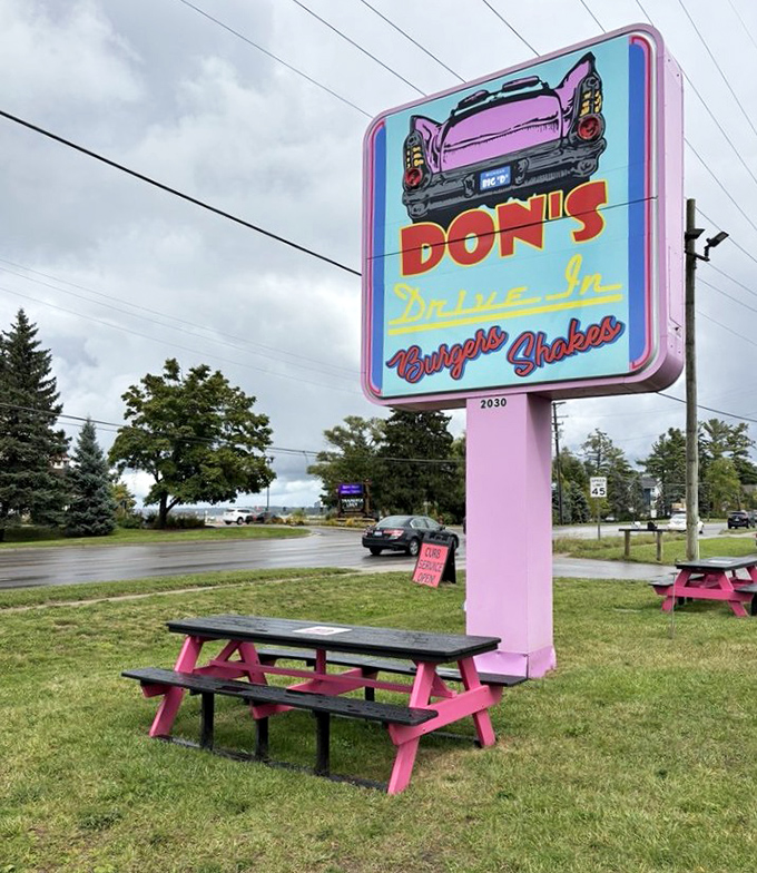 The neon sign featuring a classic pink Cadillac serves as a beacon for burger lovers and nostalgia seekers alike.