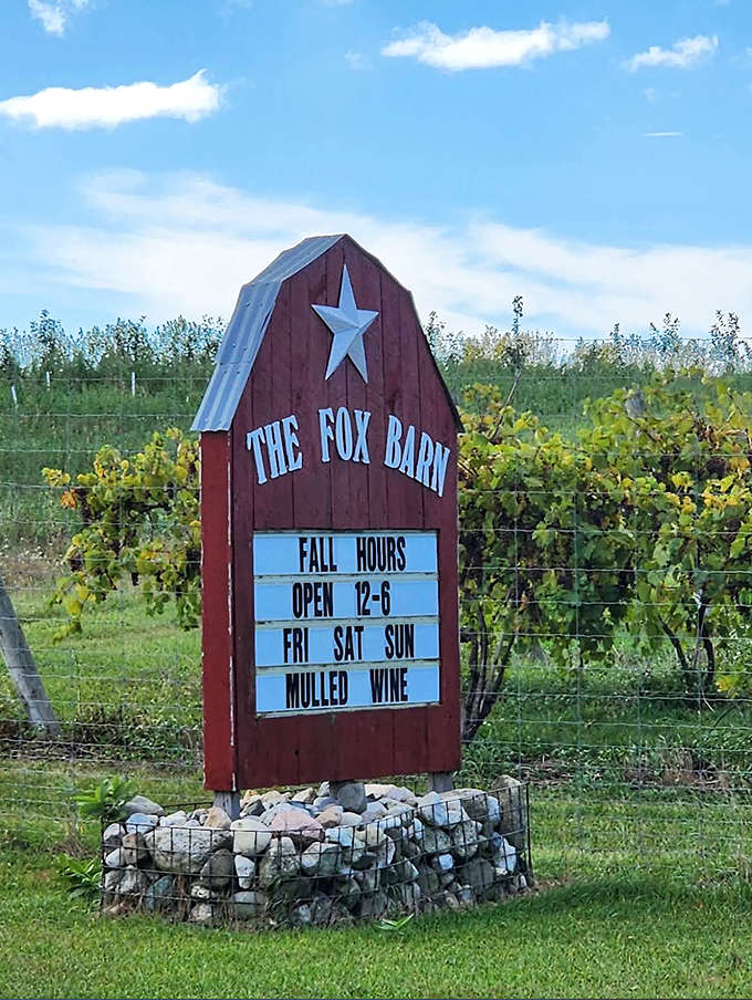 The distinctive barn-shaped sign stands sentinel by the vineyard, announcing seasonal hours and special offerings to passing wine enthusiasts.