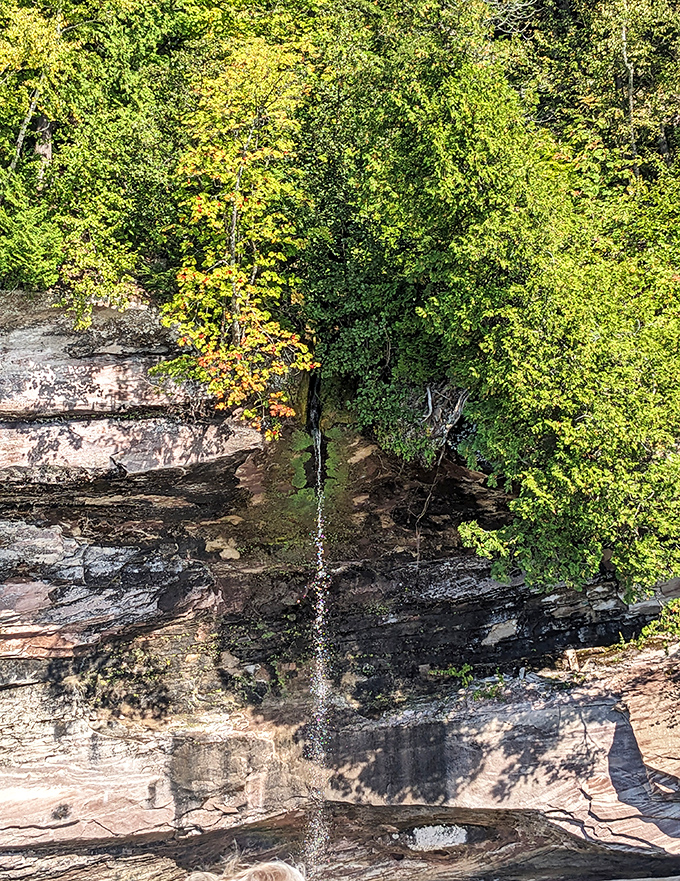 A delicate waterfall threads its way down ancient stone, demonstrating how persistence creates beauty over time.
