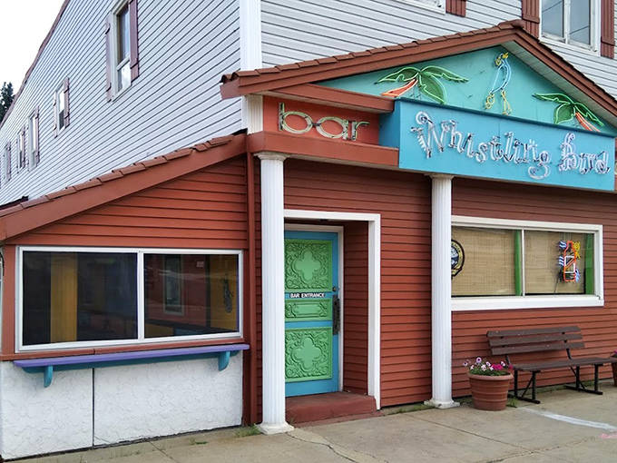 The Whistling Bird's vibrant exterior promises a Caribbean escape, with its turquoise door beckoning like a portal to warmer shores.