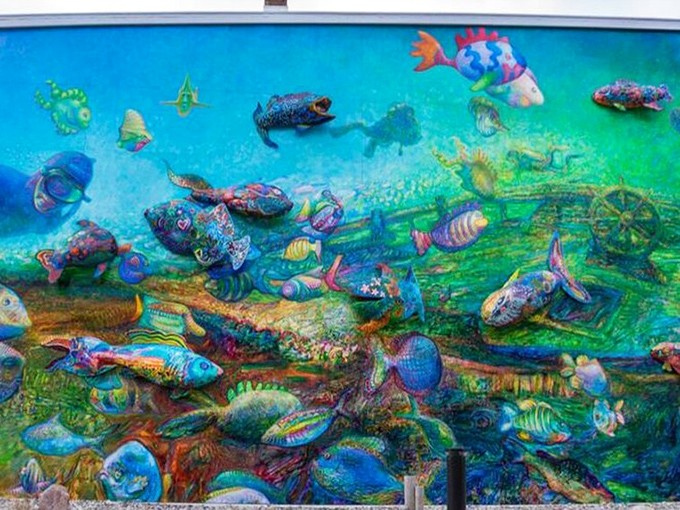 Technicolor fish seem caught mid-swim, their 3D forms creating an optical illusion so convincing you'll check your pockets for scuba gear.