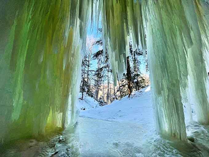 Peering through translucent ice walls reveals a magical world where sunlight filters through frozen curtains in ethereal patterns.