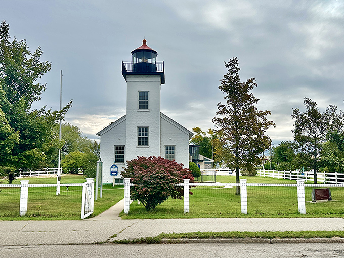 The pristine white facade and classic red roof create a postcard-perfect scene that's been welcoming sailors home since the Civil War era.