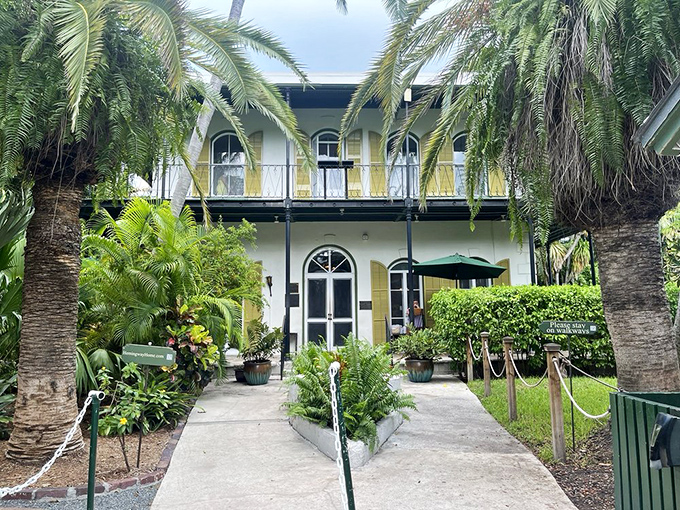 The front facade welcomes visitors with palm-framed charm and wrought-iron details that whisper stories of wild parties and quiet contemplation.