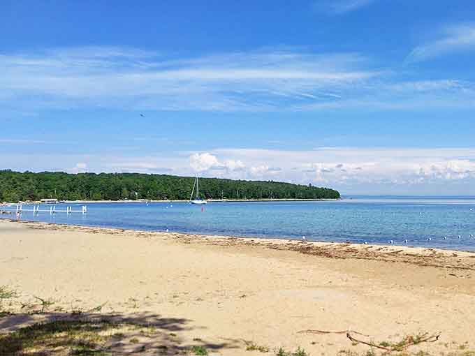 The beach's pristine shoreline curves gently along Grand Traverse Bay, where every footprint tells a story of summer adventures.