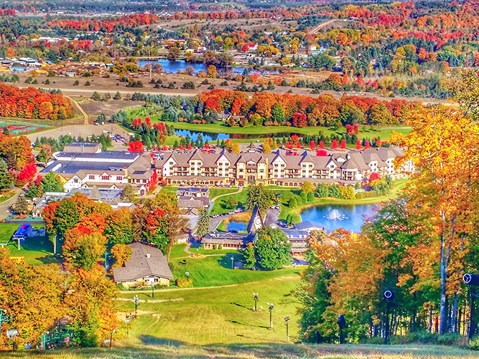 A breathtaking aerial view showcases the resort nestled among Michigan's autumn splendor, with a tapestry of red, orange, and gold foliage surrounding the property.
