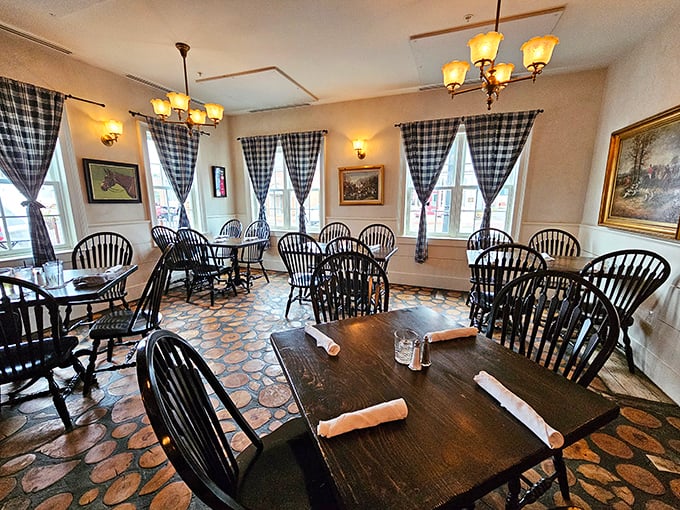Black and white checkered curtains frame Windsor chairs in this charming dining room where equestrian themes and warm lighting create an atmosphere of refined rustic elegance.