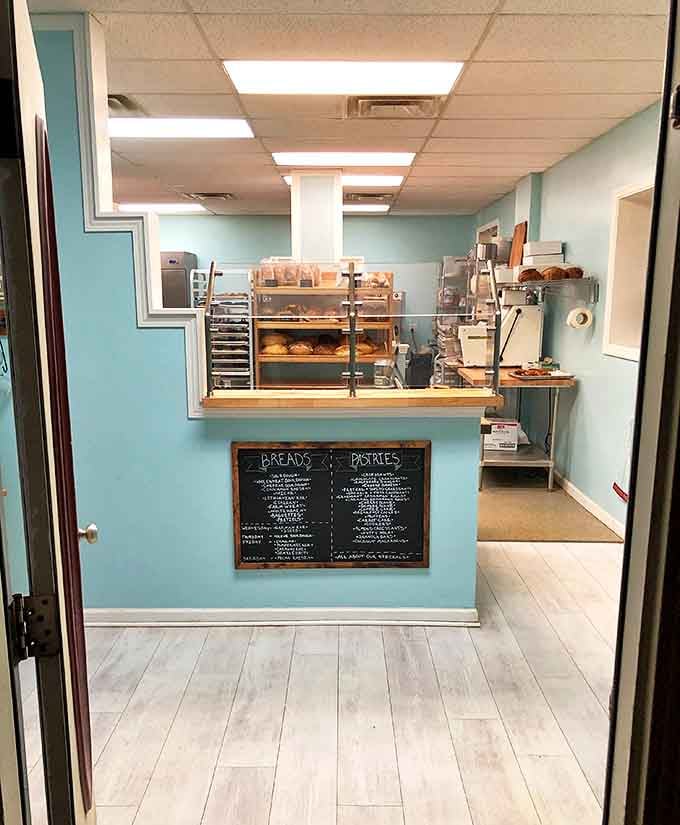 Behind the counter, a glimpse into the bakery's inner sanctum where flour-dusted magic happens daily. The light blue walls create a canvas for carbohydrate artistry.