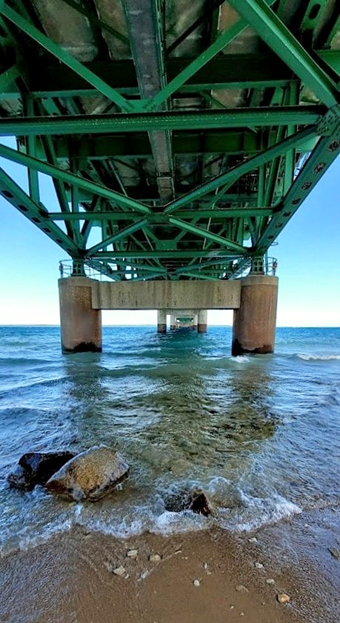 Beneath the engineering marvel, massive steel trusses and concrete pillars support five miles of roadway while waves crash below.