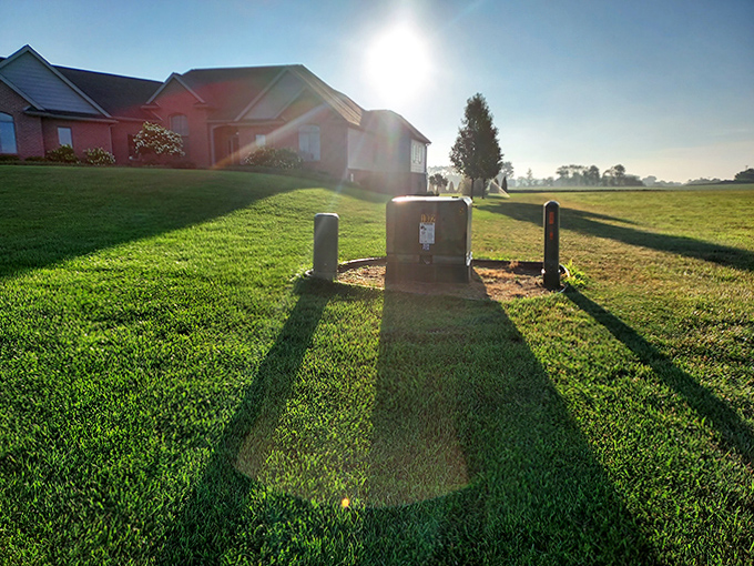 A utility box sits sentinel on a manicured lawn, the unsung hero of suburban infrastructure with a view better than most office workers.