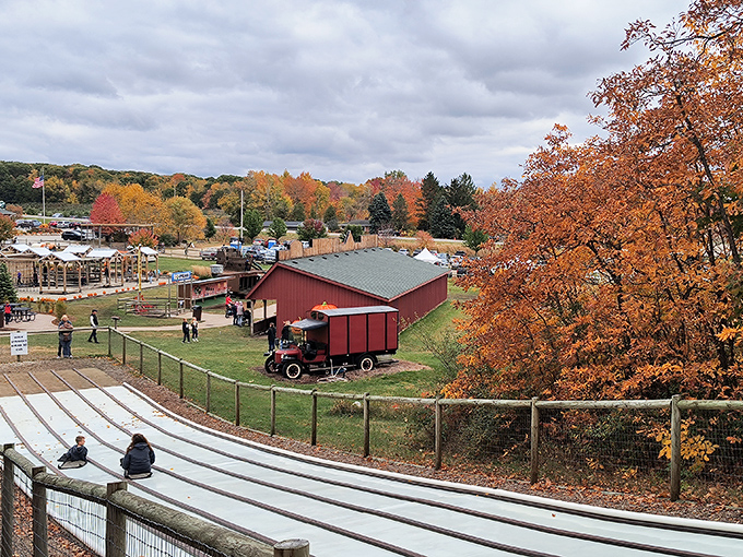 Fall's fiery colors frame the farm's attractions, where families enjoy seasonal fun while a vintage train chugs along the perimeter.