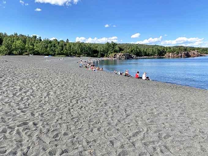 Visitors enjoy the unique black sand shoreline while the cool waters of Lake Superior beckon.