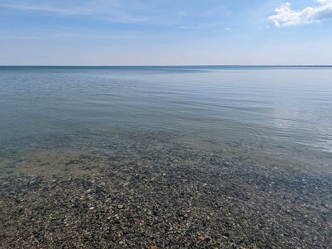 The glassy surface of Lake Huron stretches to the horizon, creating a mirror-like effect that doubles the beauty of Michigan's endless sky.