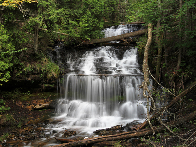The multi-tiered waterfall creates a mesmerizing display as water dances down moss-covered rocks, each level adding to the symphony.