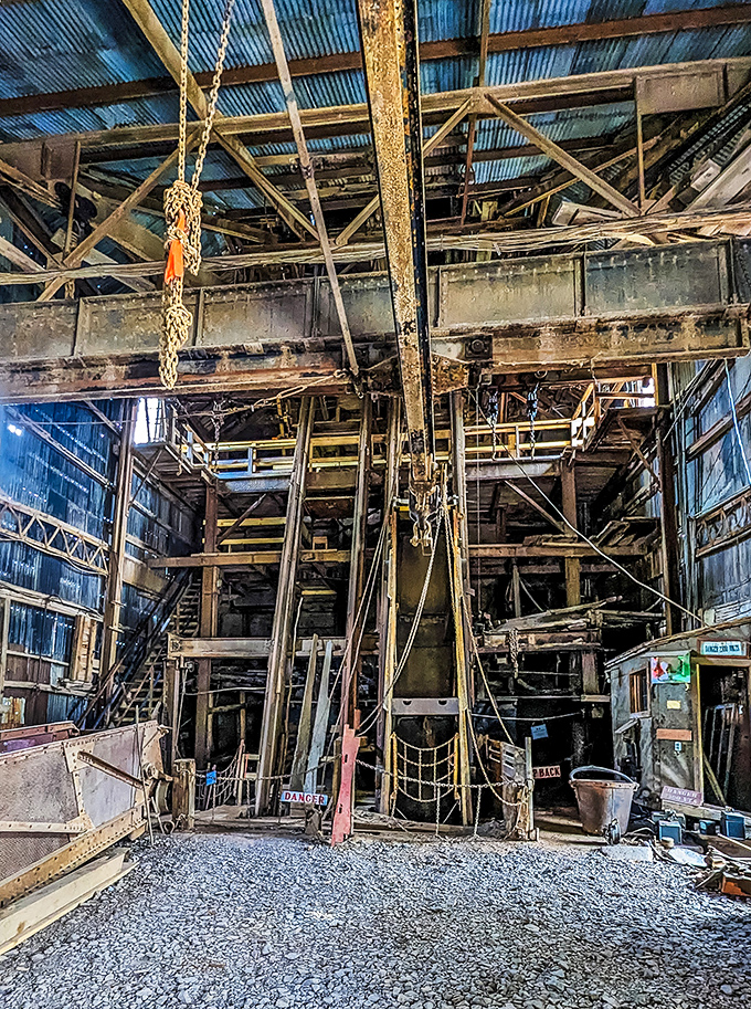Inside the abandoned mine buildings, cathedral-like spaces reveal a mechanical wonderland where shafts of light illuminate frozen gears and silent machinery.
